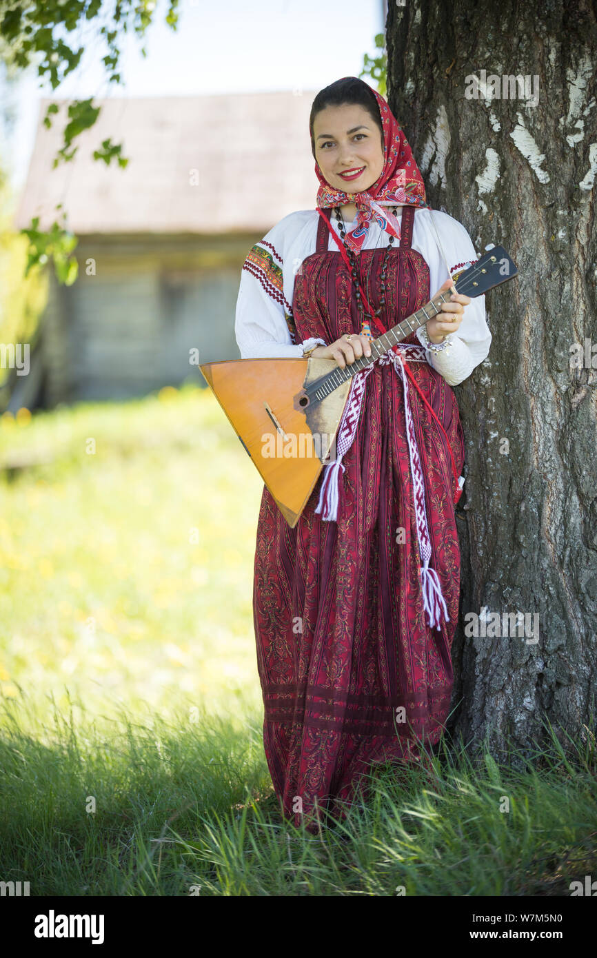 Young attractive woman in traditional russian clothes standing under a ...