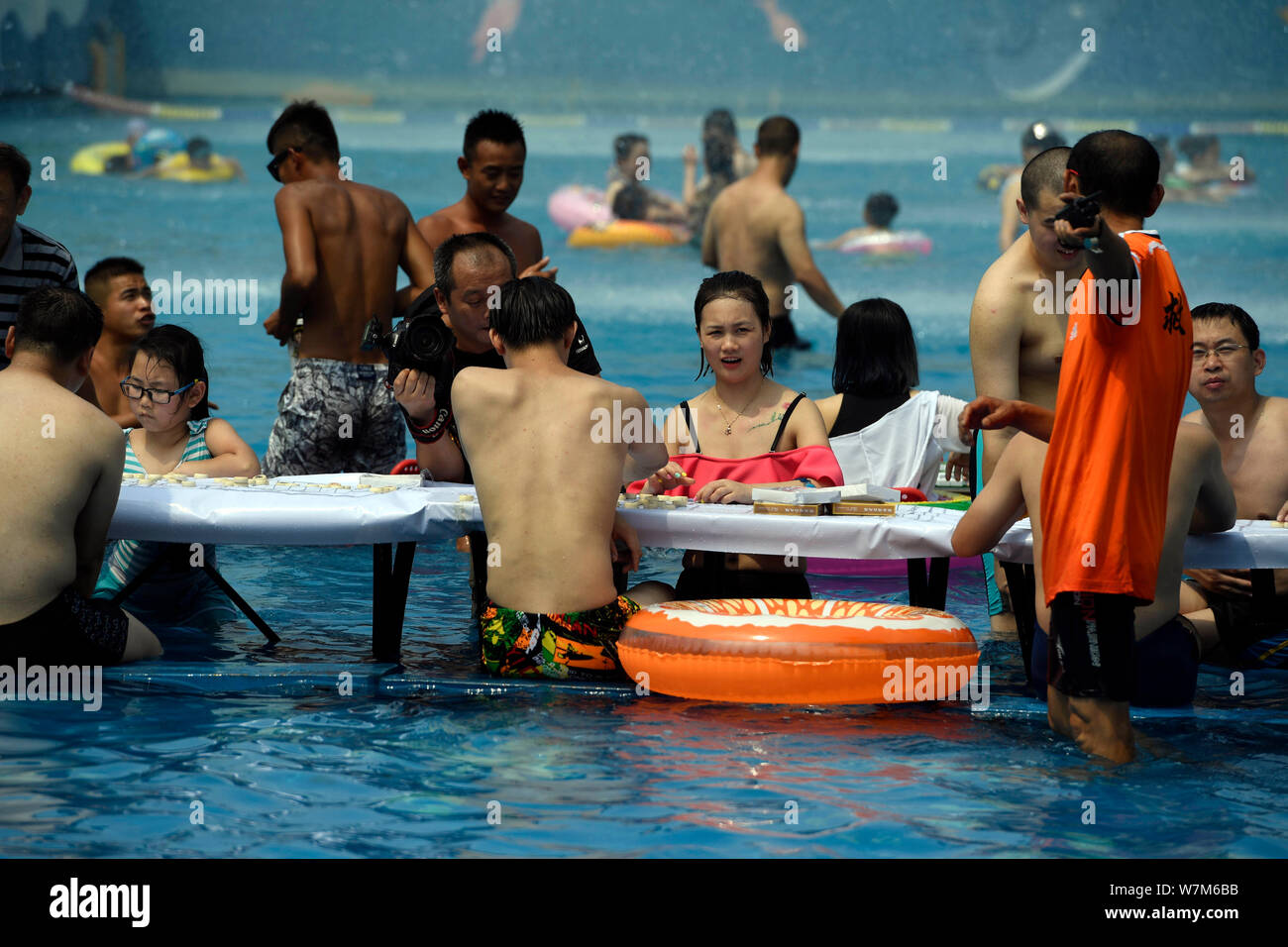 Chinese holidaymakers play Chinese chess in the water at a water park ...