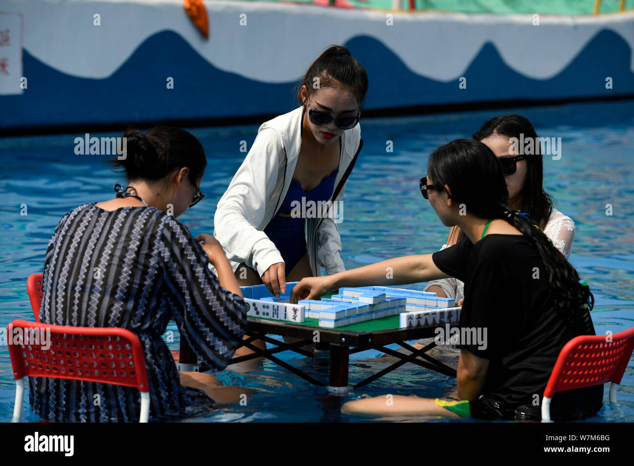 Chinese holidaymakers play mahjong in the water at a water park in ...