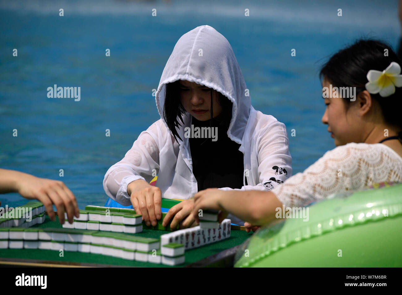 Chinese holidaymakers play mahjong in the water at a water park in ...