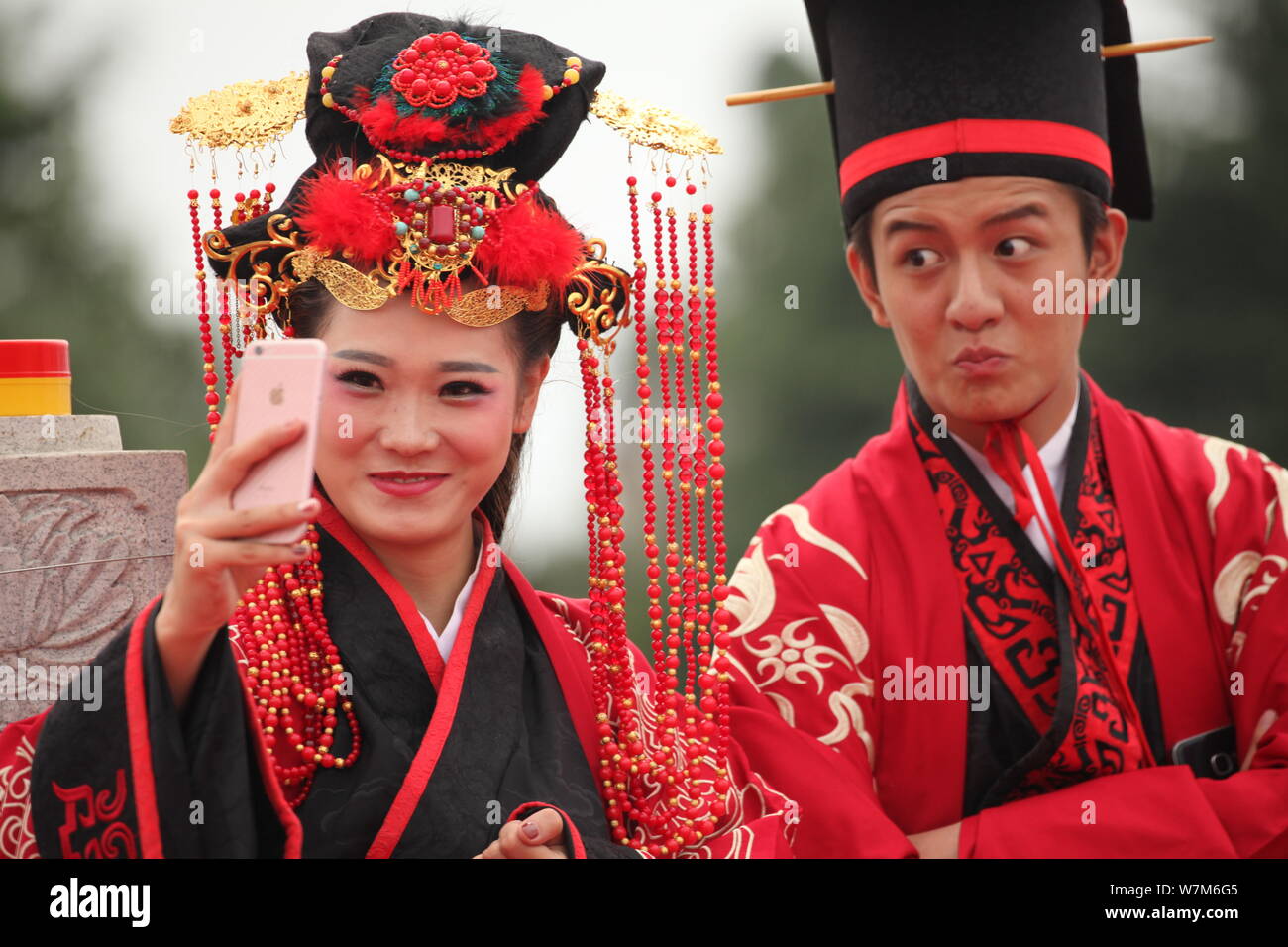 A couple of newlyweds dressed in traditional Han costumes take selfies ...