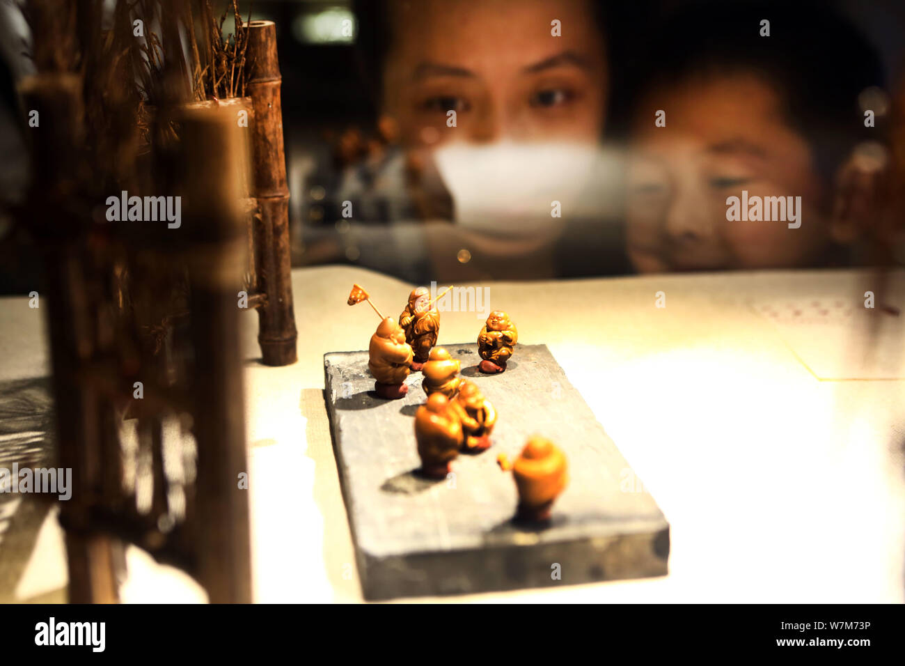Visitors look at fruit pit carvings on display during a carving ...