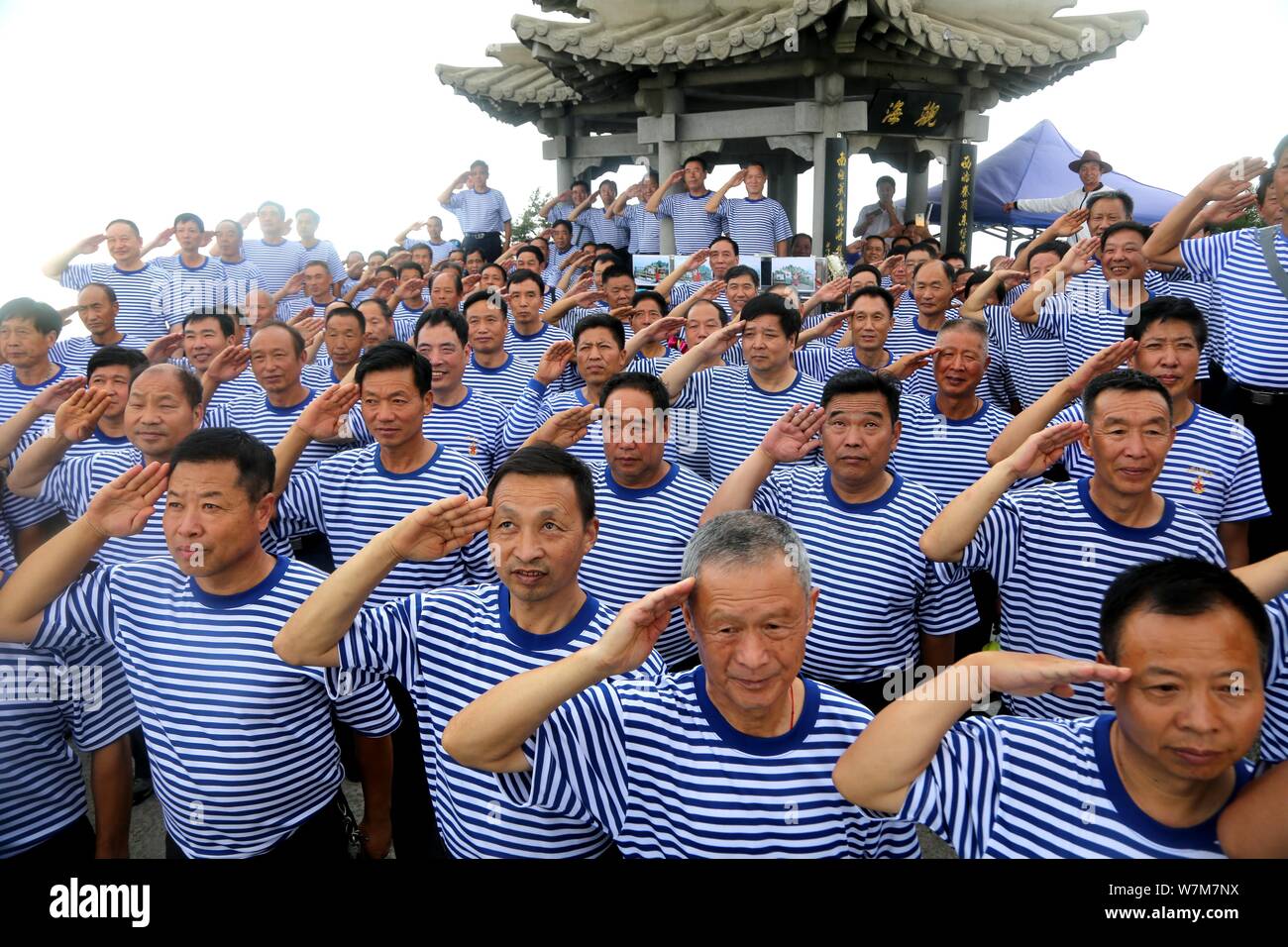 Chinese veterans salute after climbing to the peak of Funiu Mountain to ...