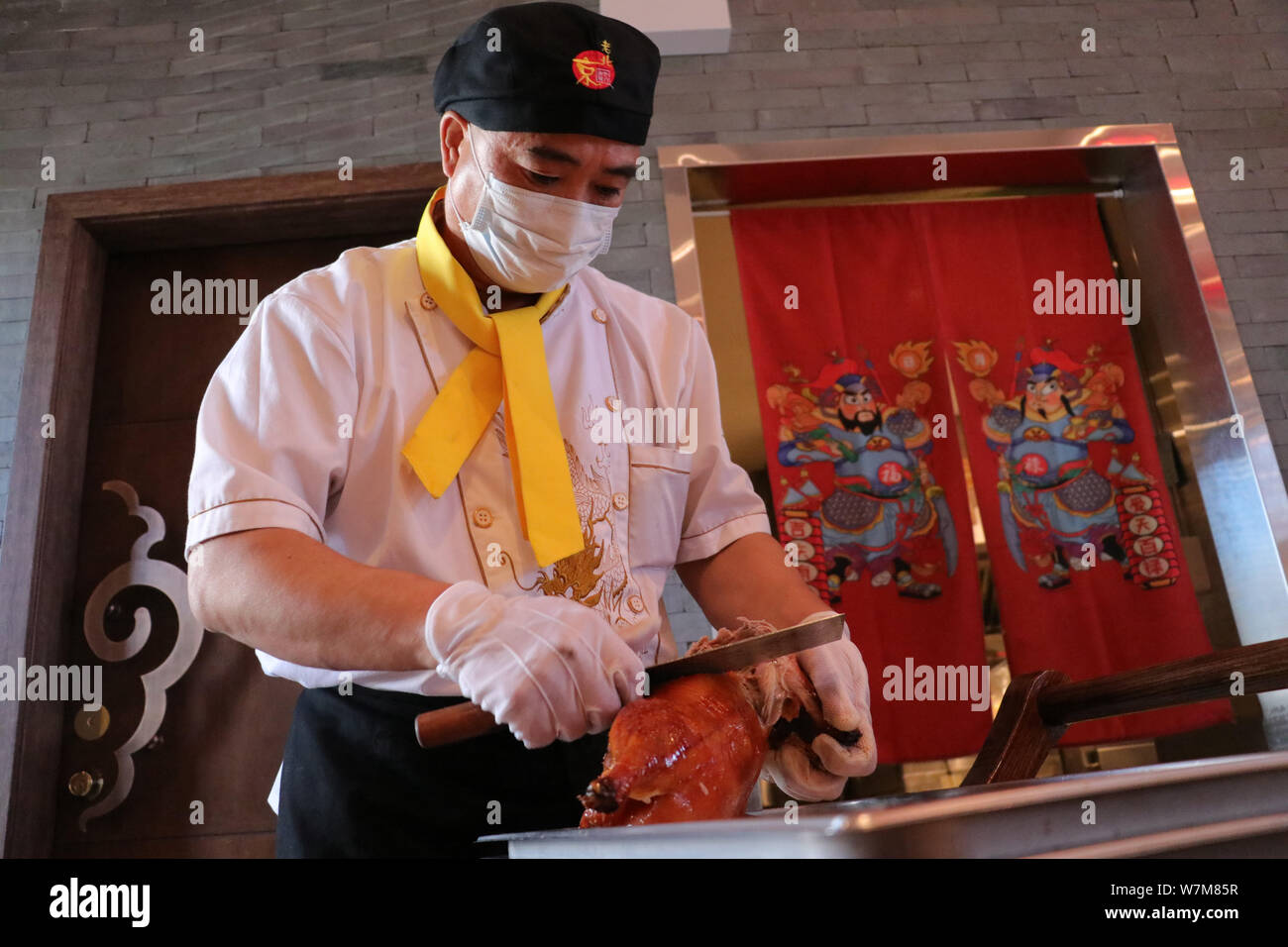 A Chinese chef slices a roasted Peking Duck to put on the crisps and ...