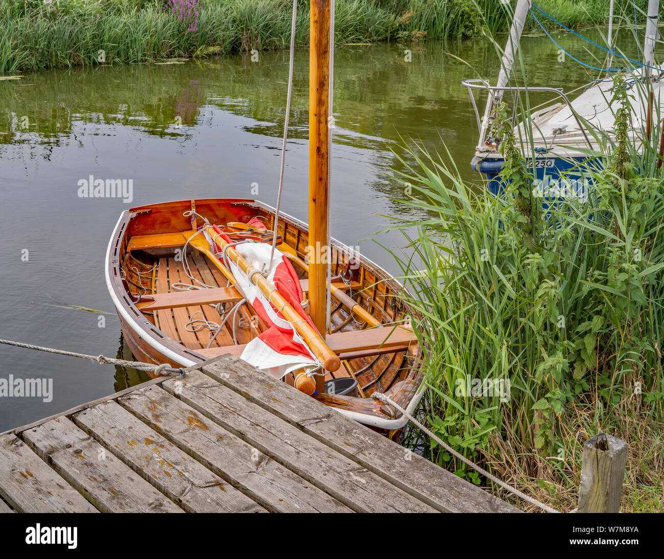 A small wooden dinghy moored up to a wooden quay heading on the River ...