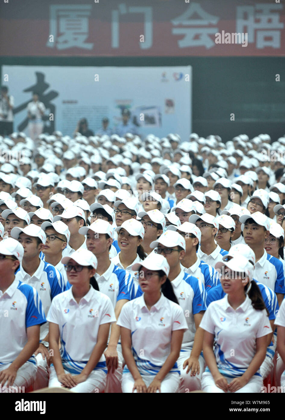Chinese volunteers dressed in uniforms watch representatives displaying ...