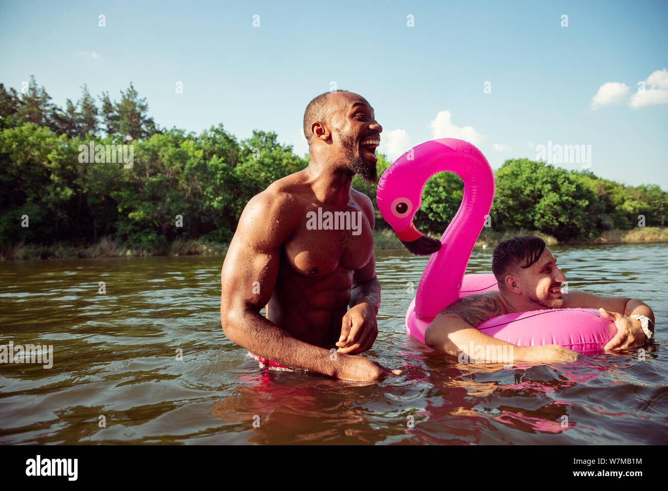 Happy group of friends having fun while laughting, splashing water and ...