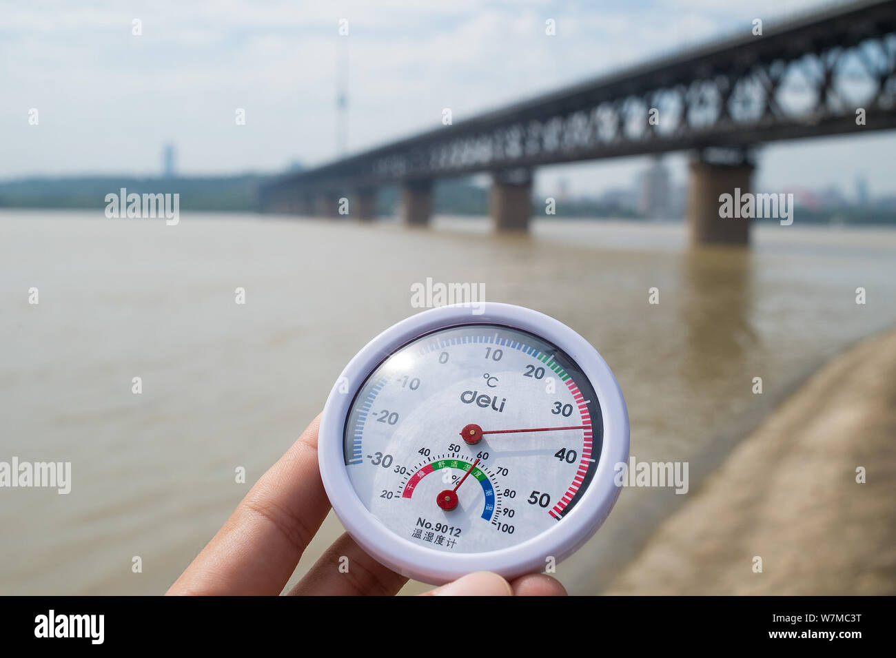 A local resident displays a thermometer showing the current temperature ...