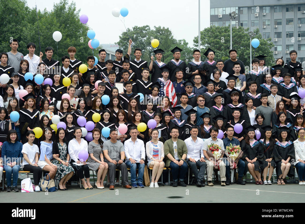 Graduates dressed in academic gowns holding ballons pose for a group ...