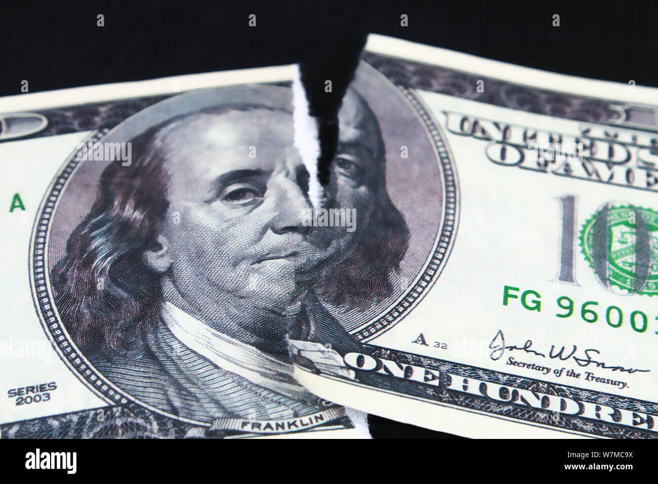 Torn ripped devalued one hundred dollar bank note on a black background ...