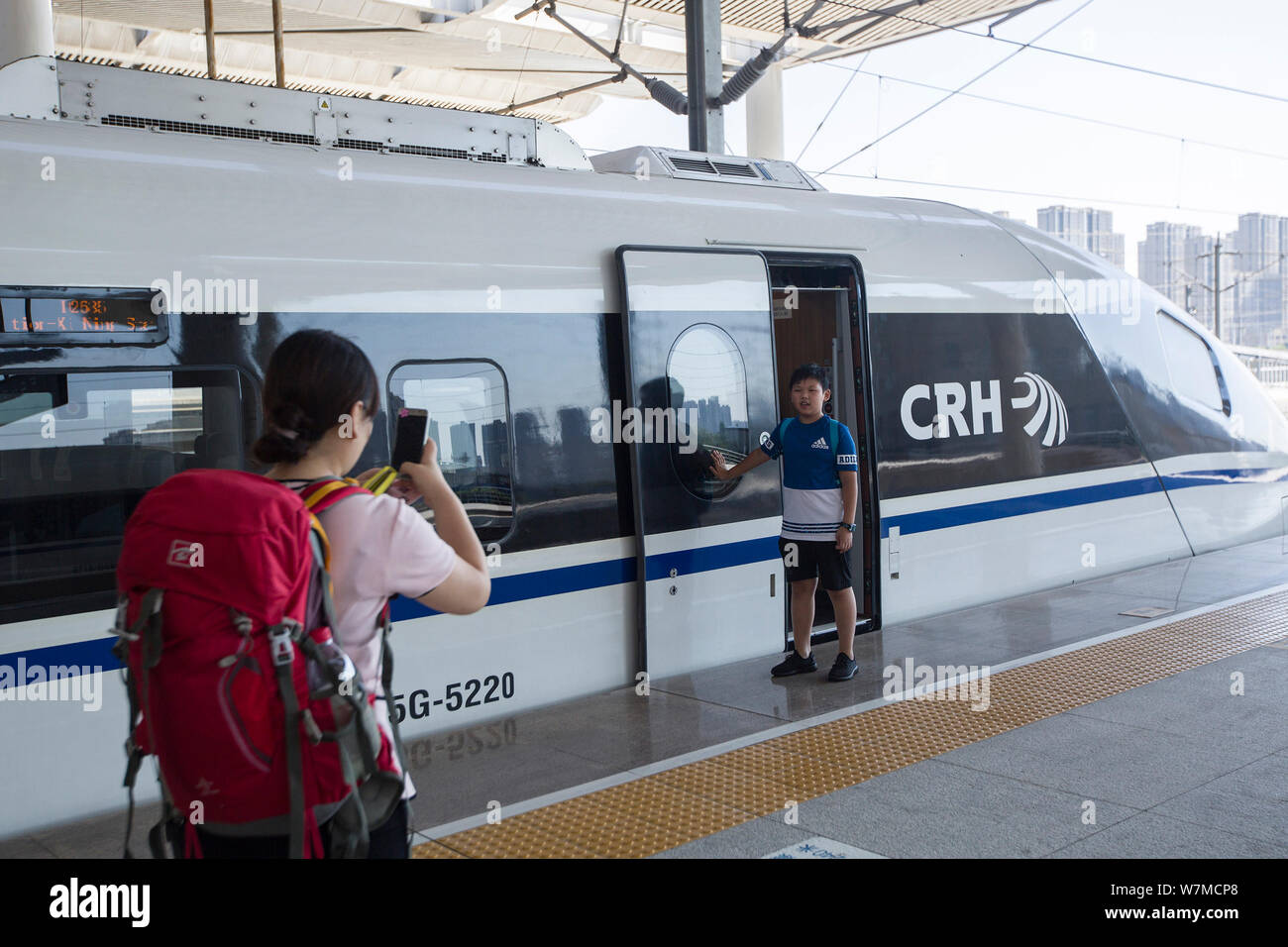 A passenger takes photos in front of a CRH5G (China Railway High-speed ...