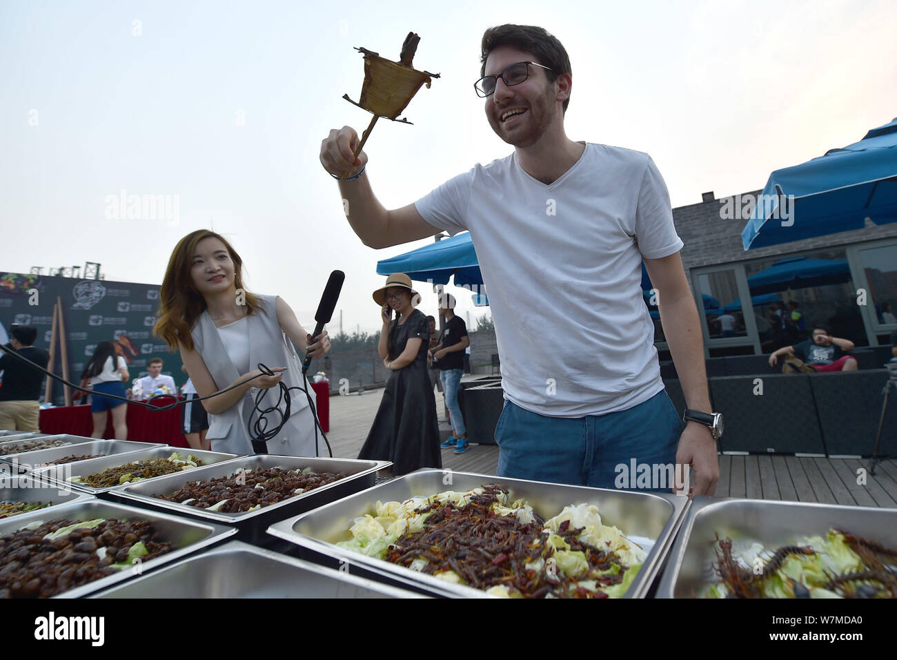 A foreigner tries out a fried wall lizard during a challenge to eat ...