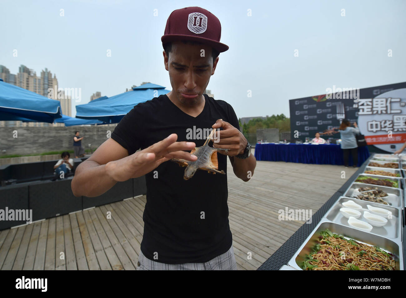 A foreigner tries out a fried wall lizard during a challenge to eat ...