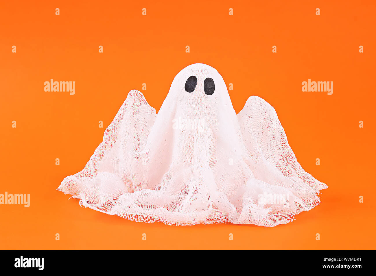 Halloween ghost of starch and gauze on orange background. Gift idea ...