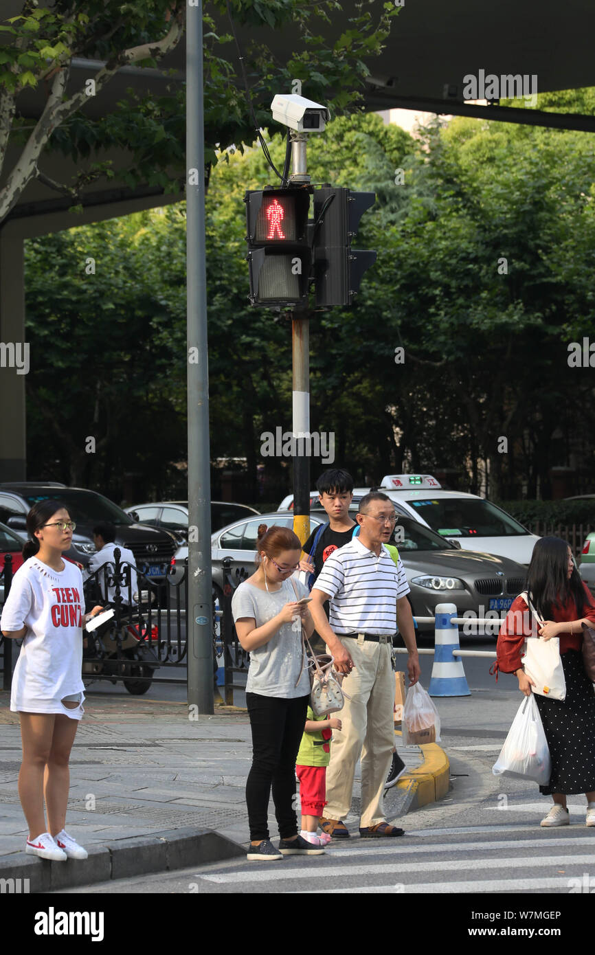 Chinese citizens wait for a red light to turn green in front of a trial ...