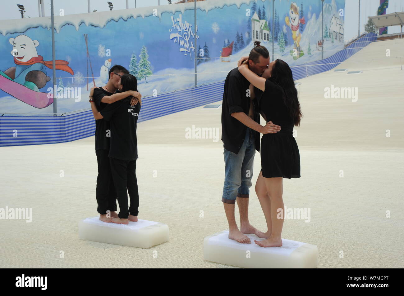 Lovers standing in an ice block kiss each other during a kissing ...
