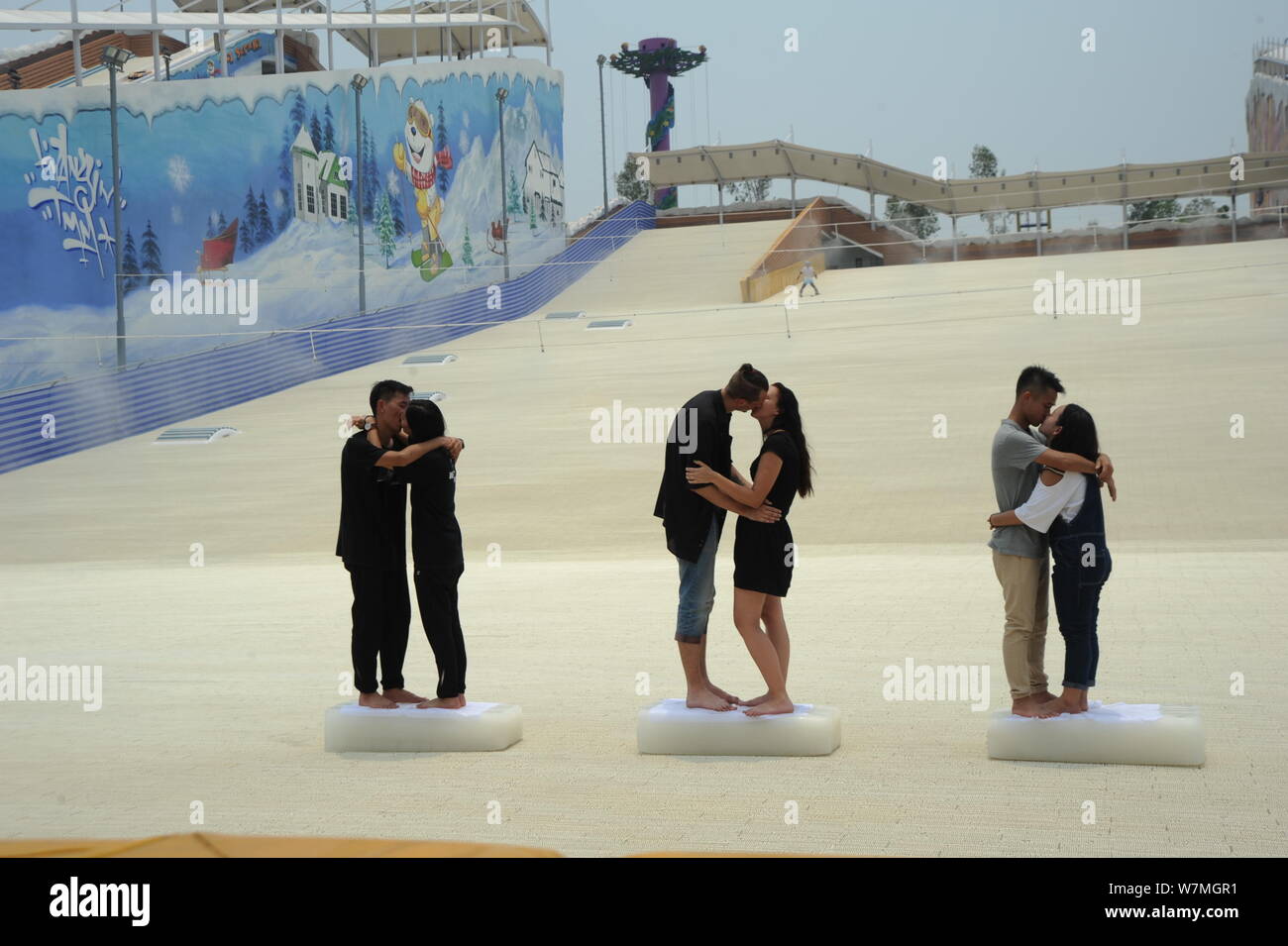 Lovers standing in an ice block kiss each other during a kissing ...
