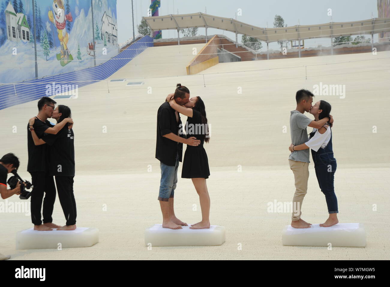 Lovers standing in an ice block kiss each other during a kissing ...