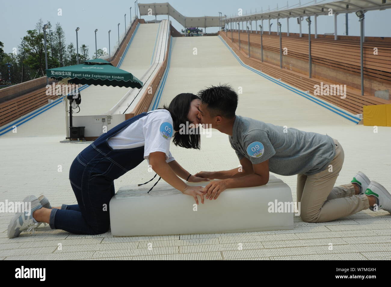 A couple of lovers leaning on an ice block kiss each other during a ...