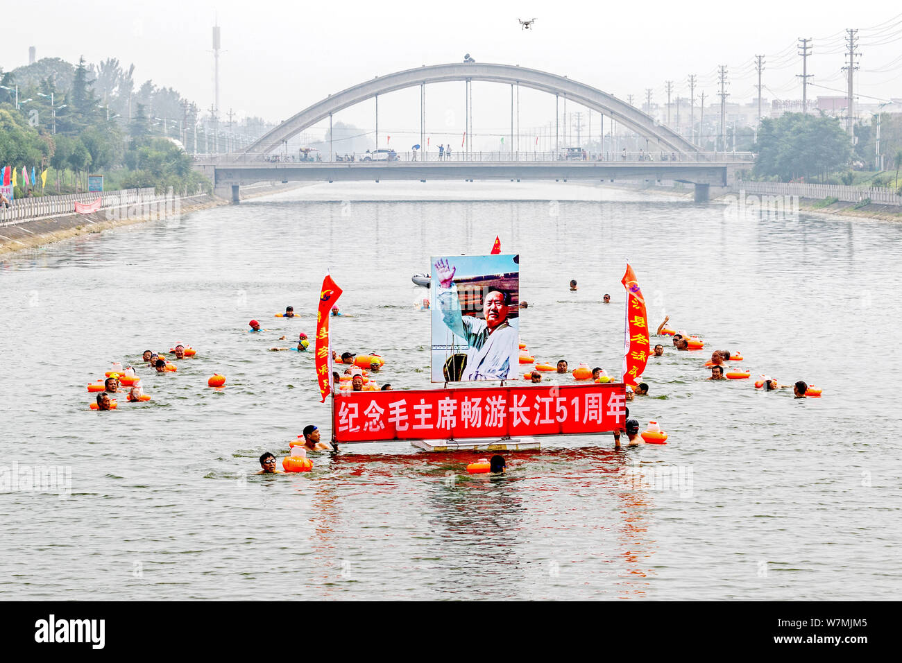 More than 50 swimmers swim across Dagong River, holding high a cutout ...