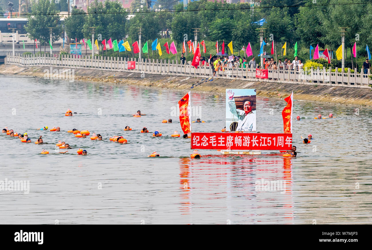 More than 50 swimmers swim across Dagong River, holding high a cutout ...