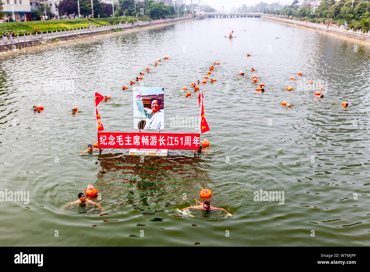 More than 50 swimmers swim across Dagong River, holding high a cutout ...