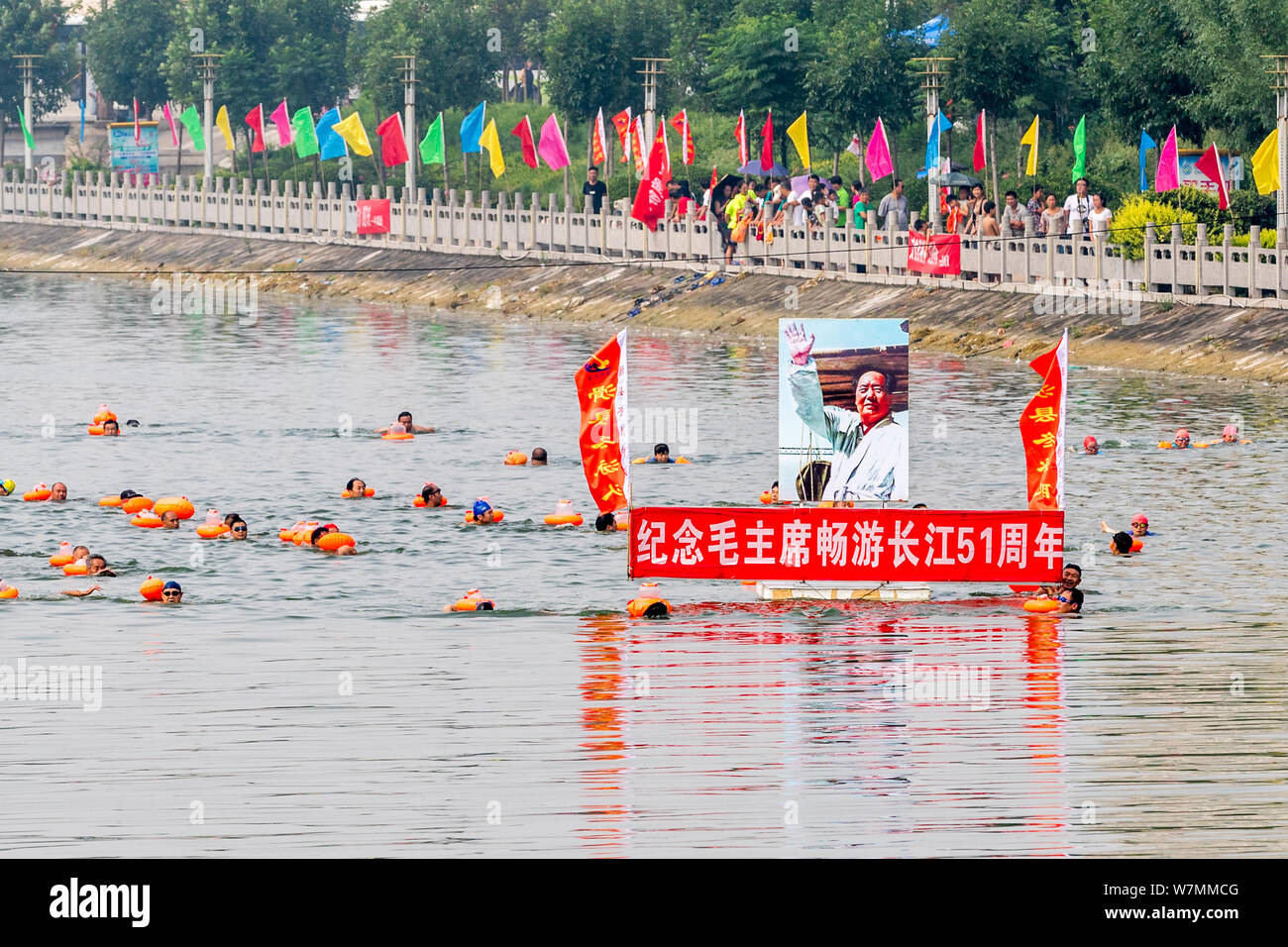 More than 50 swimmers swim across Dagong River, holding high a cutout ...