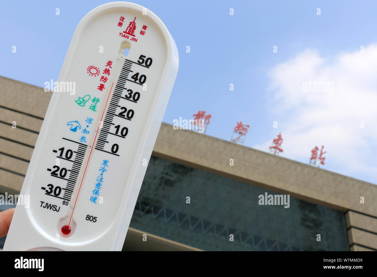 A local resident displays a thermometer showing the current temperature ...