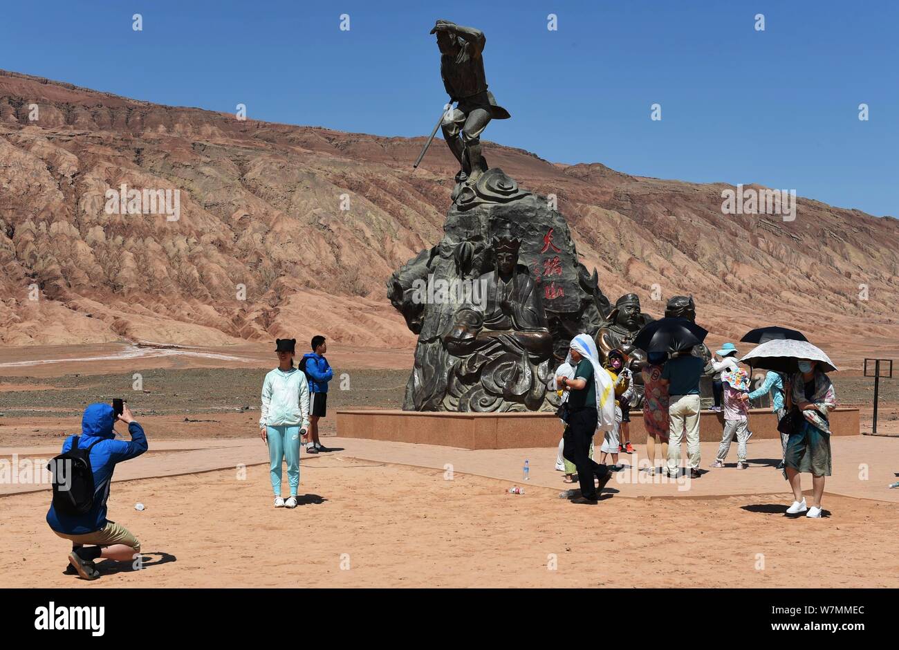 Tourists pose for photos with the landmark sculpture at the foot of the ...