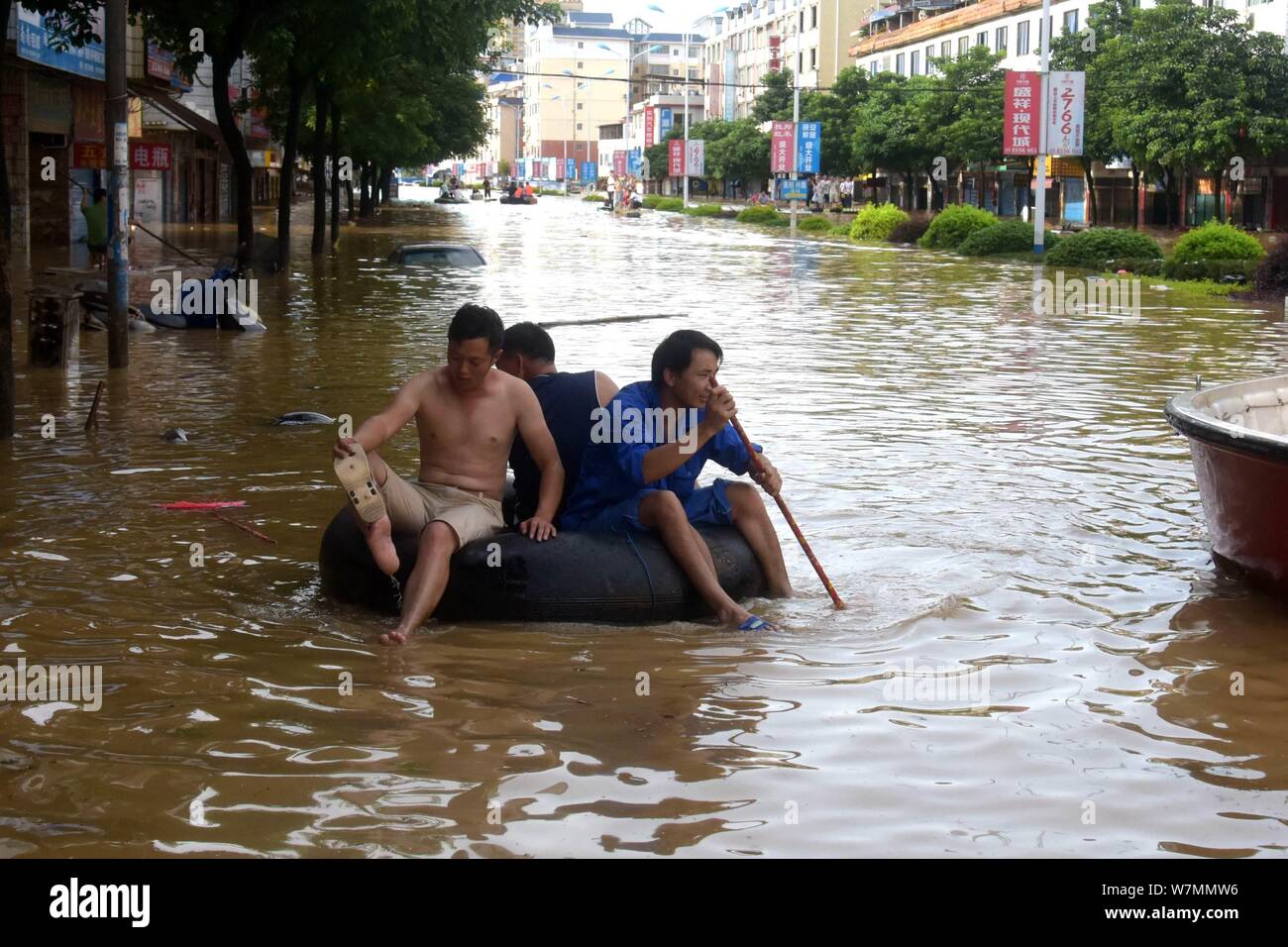 Local residents take an inflatable life boat on a flooded street caused ...