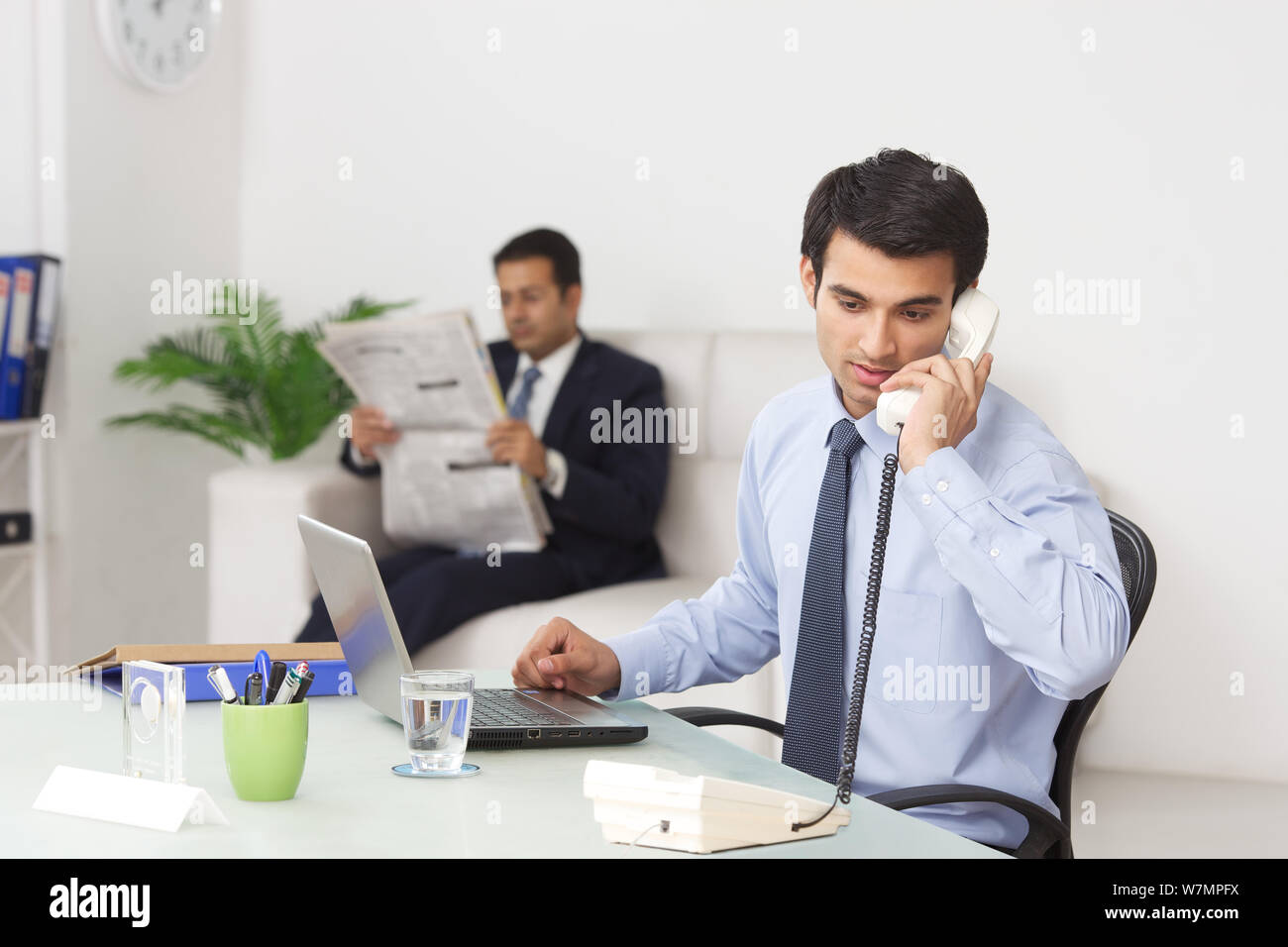 Financial advisor talking on landline phone with a businessman waiting ...