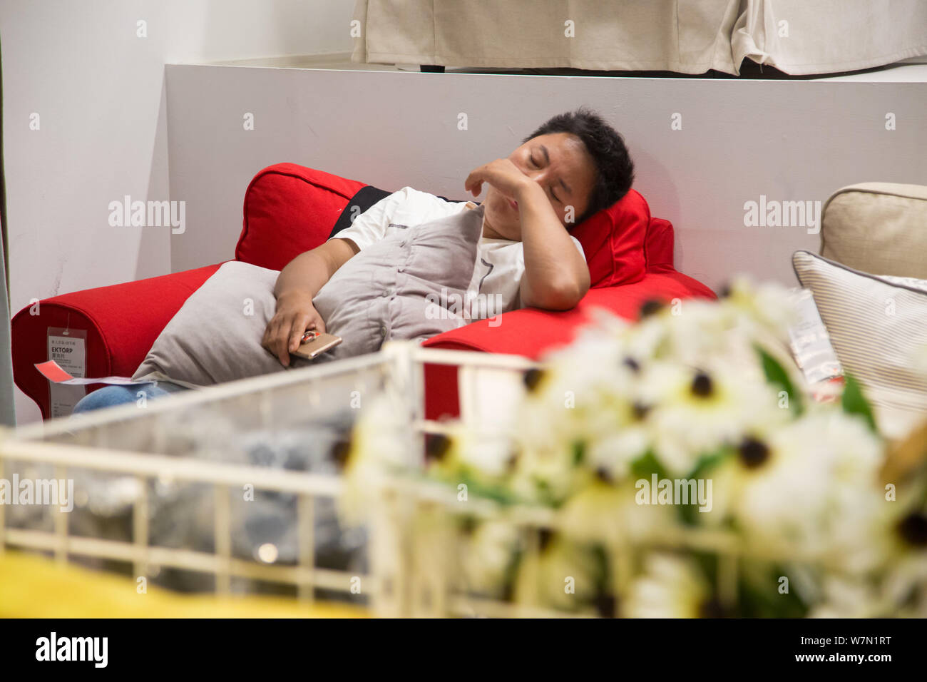 A Chinese customer takes a nap on a sofa displayed at the furnishing ...