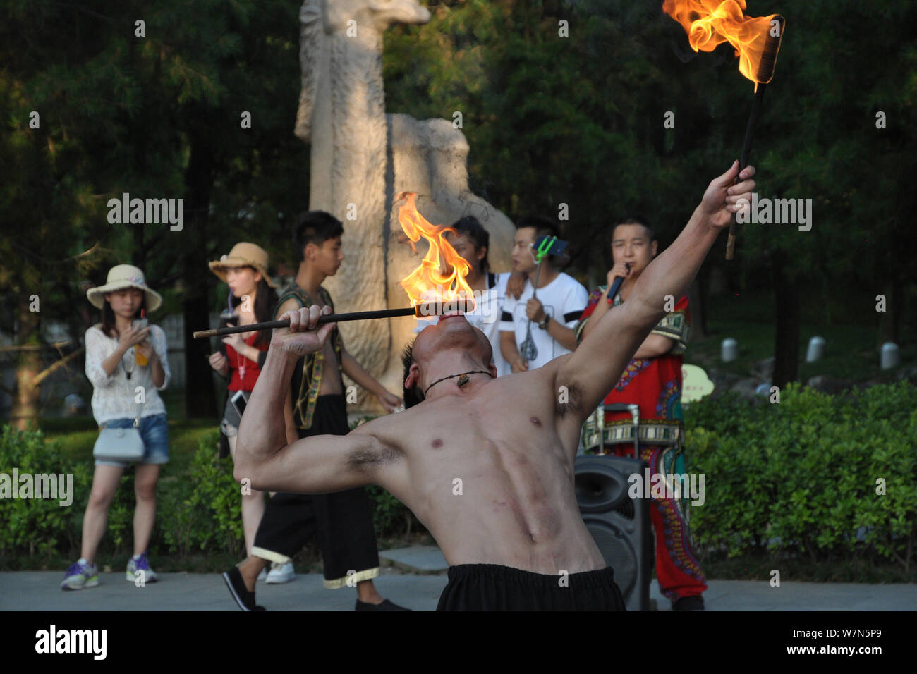 A Chinese artist performs for tourists with fire on Toufu, the first ...