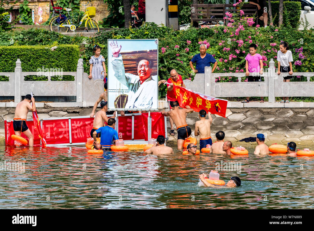 More than 50 swimmers swim across Dagong River, holding high a cutout ...