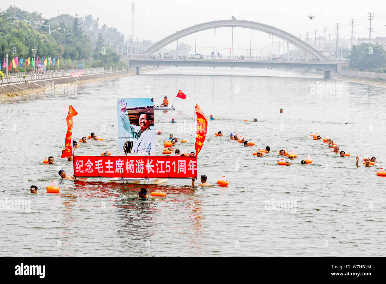 More than 50 swimmers swim across Dagong River, holding high a cutout ...