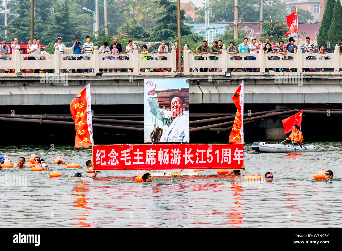 More than 50 swimmers swim across Dagong River, holding high a cutout ...