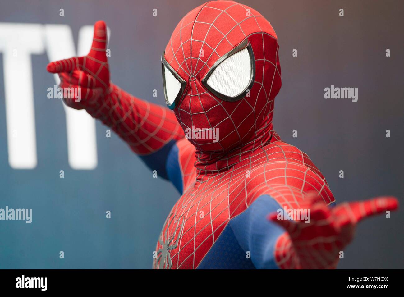 A staff member dressed as Spiderman poses for photos during a super ...