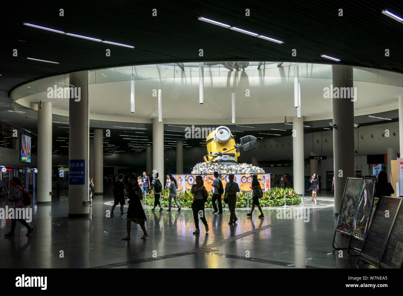 Passengers walk past the giant sculpture of Minions with a height of ...