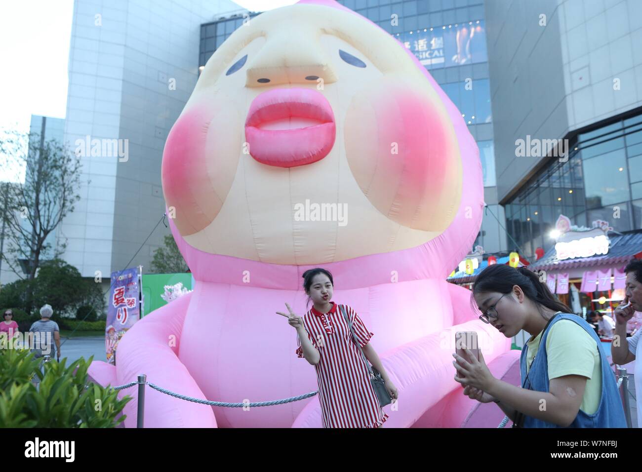 Pedestrians take photos with a 6-meter-tall giant inflatable Kobitos, a ...