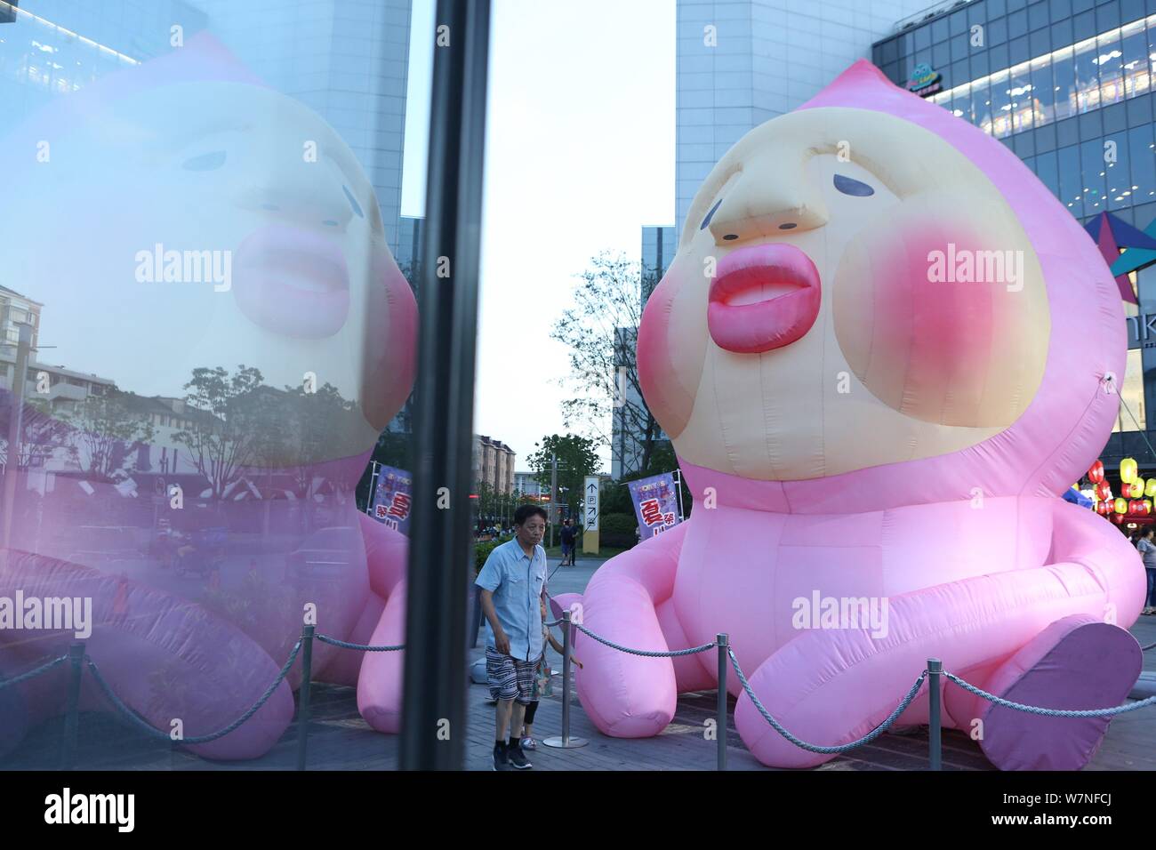 A pedestrian walks past a 6-meter-tall giant inflatable Kobitos, a ...