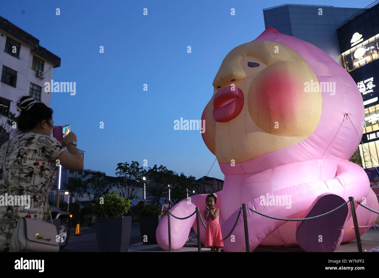 Pedestrians take photos with a 6-meter-tall giant inflatable Kobitos, a ...