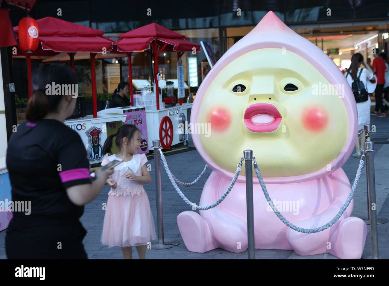 Pedestrians take photos with a sculpture of Kobitos, a popular Japanese ...