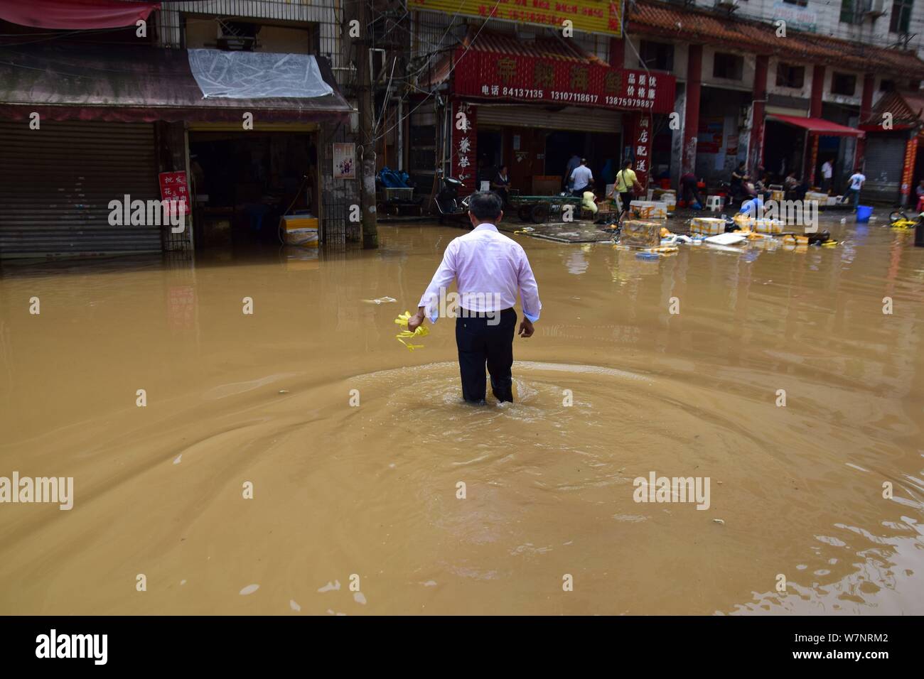 A local resident walks on a flooded street caused by heavy rain in ...