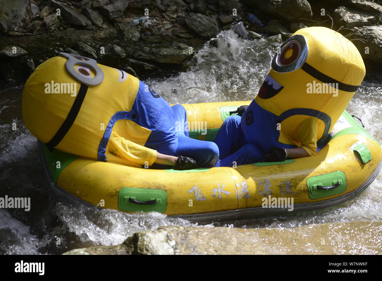 Tourists in Minion costumes enjoy leisure time on rubber rafts at a ...
