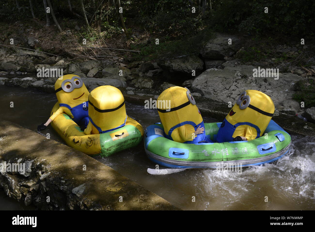 Tourists in Minion costumes enjoy leisure time on rubber rafts at a ...