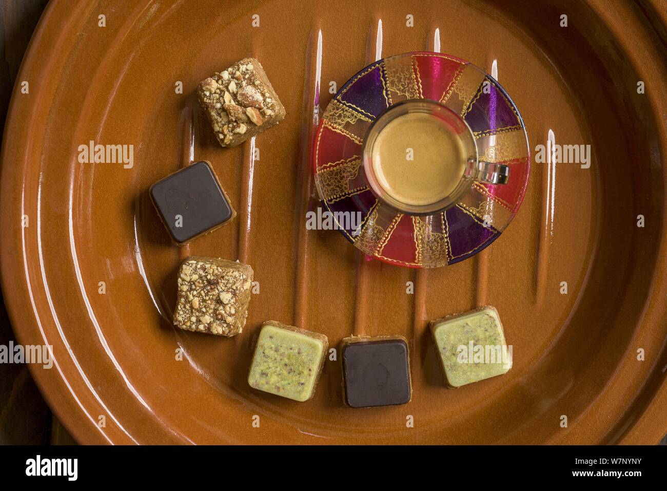 Overhead shot of different types of square-shaped sweets with tea on a ...