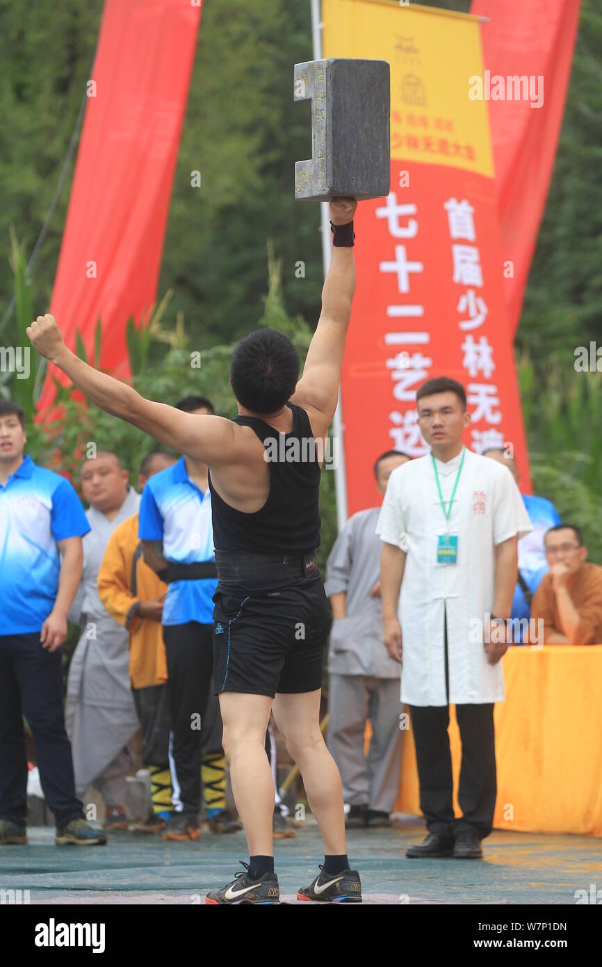 A competitor lifts a stone dumbbell in the form of an old-fashioned ...