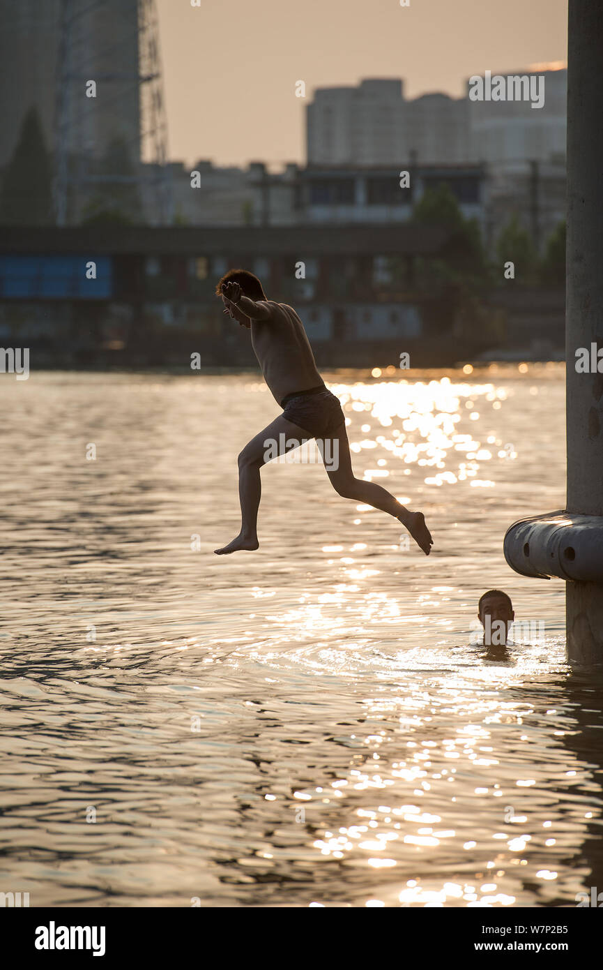 A citizen jumps into the floodwater from the flooded Yangtze River ...