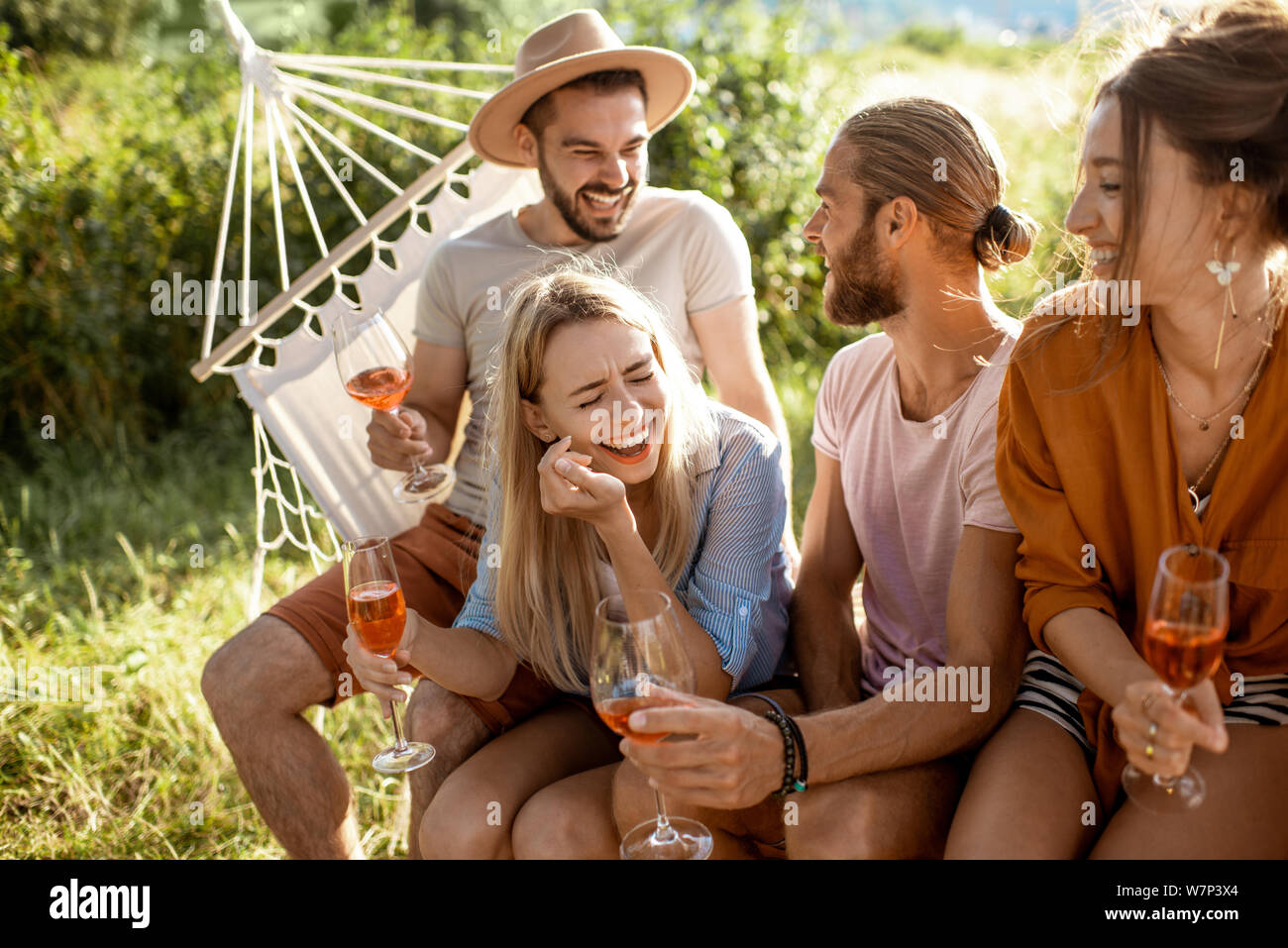 Portrait of a group of cheerful friends sitting together on the hammock ...