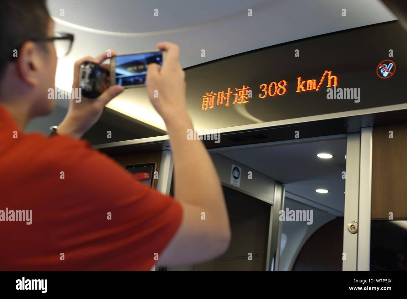 A passenger takes photos of a screen displaying the current train speed ...